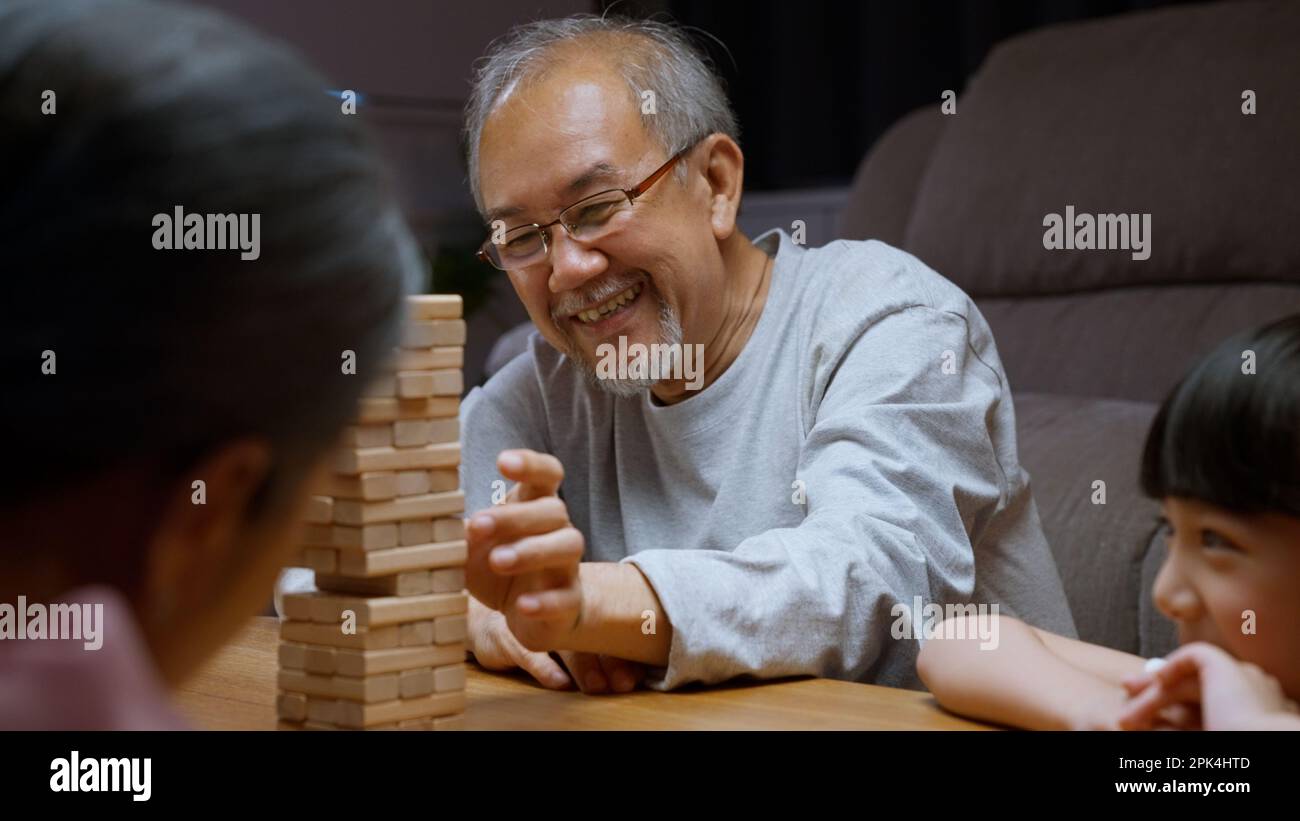 Healthy grandfather playing wooden game with granddaughter happily ...