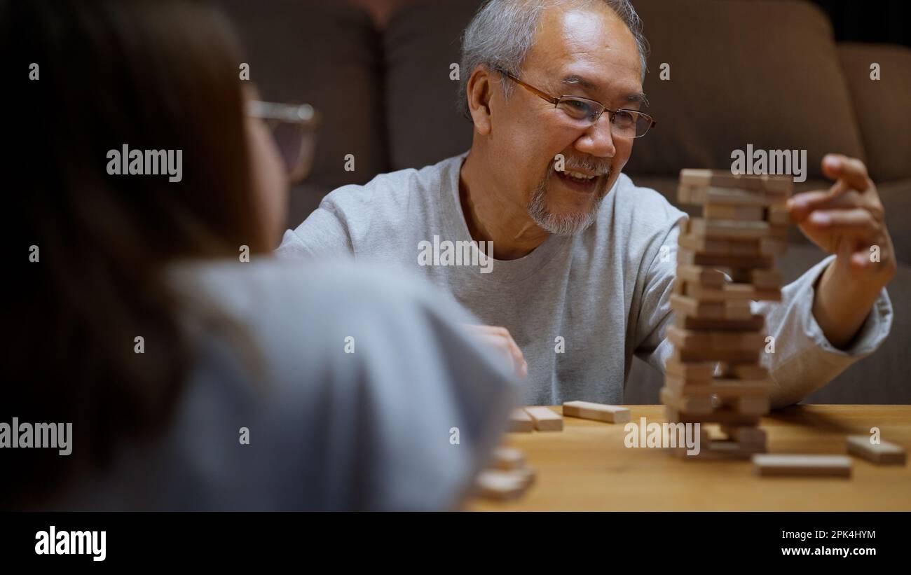 Healthy grandfather playing wooden game with granddaughter happily ...