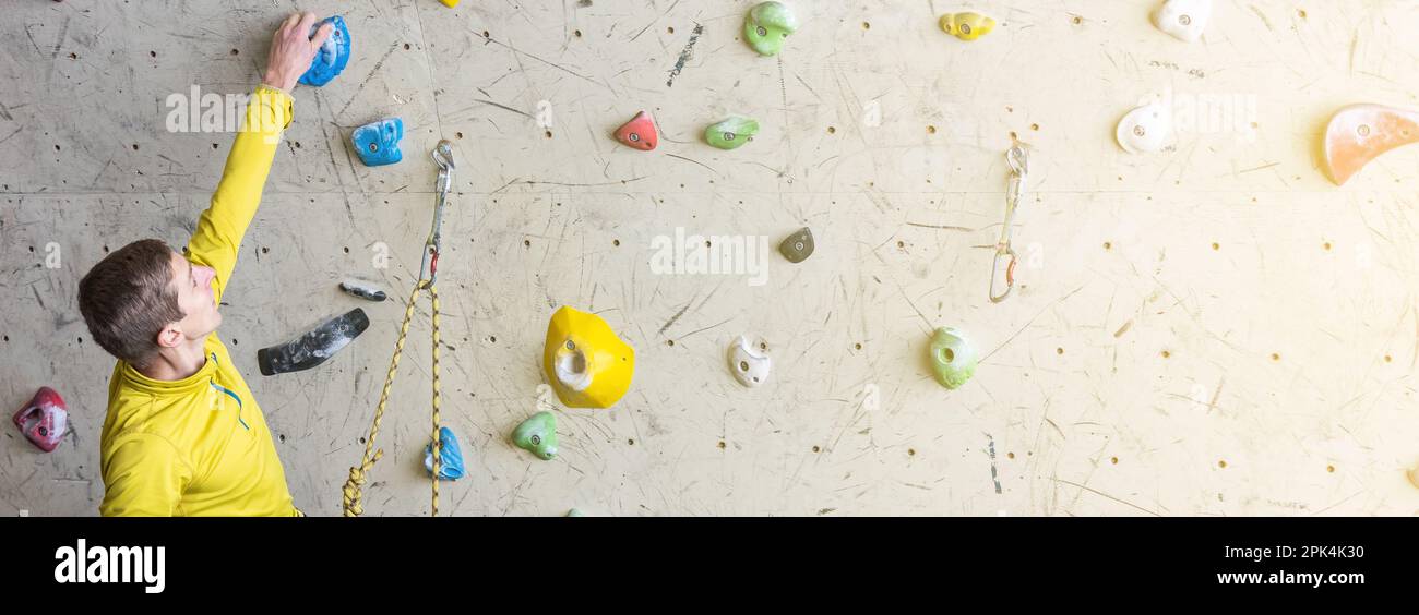 Young climber climbing on a boulder wall indoor, rear view, concept of ...