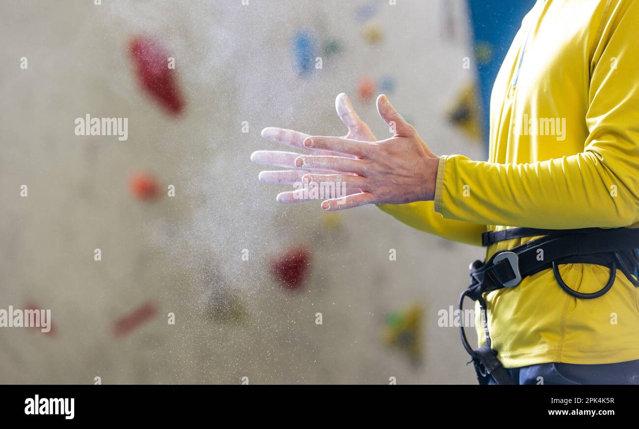 Athletic young man using magnesium for dry hands, dust flies from ...