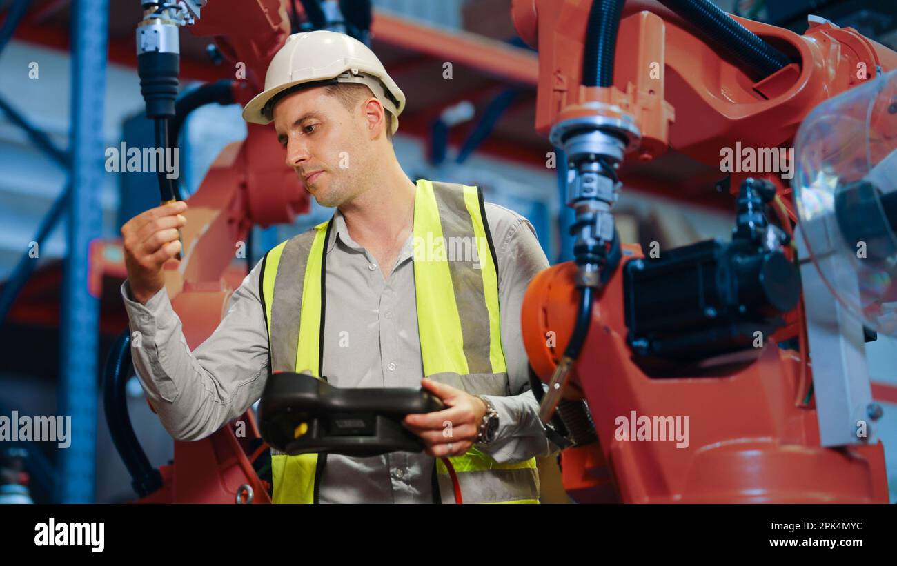 Engineer holding remote control controlling industrial machine in the ...