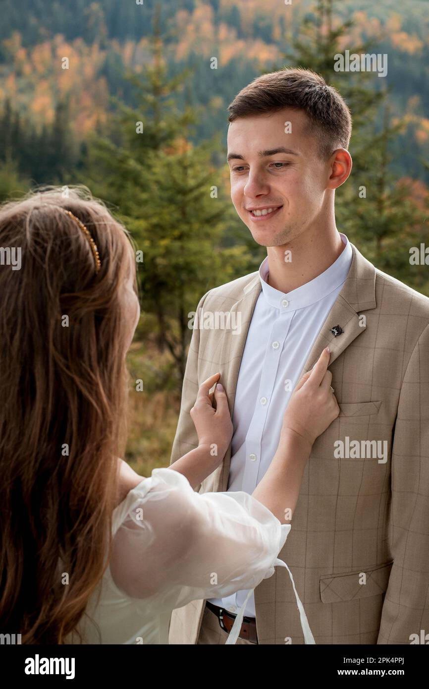 The bride looks at the groom with loving eyes. Smiling newlyweds look ...