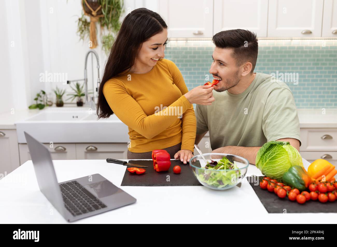 Beautiful young woman feeding her boyfriend while making dinner Stock ...
