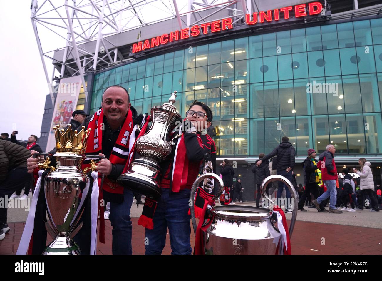 Fans hold up replica trophies outside the stadium before the Premier ...