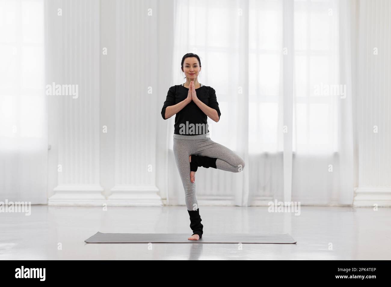 Beautiful young woman doing tree pose during yoga meditation in the ...