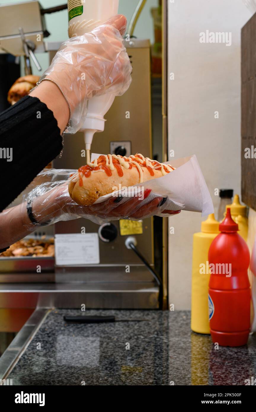 The process of making a hot dog, a worker fulfills a customer's order ...
