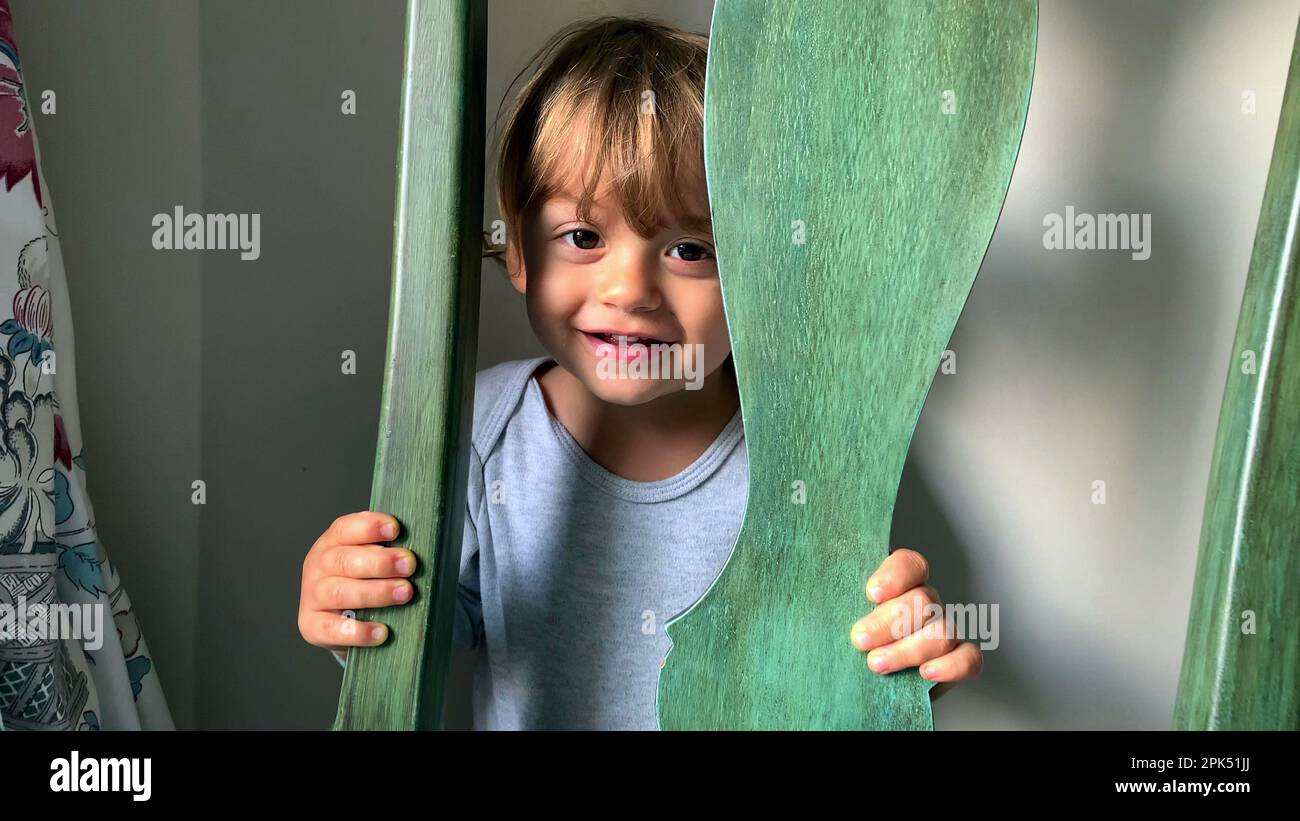 Cute adorable child infant boy hides behind chair furniture Stock Photo ...