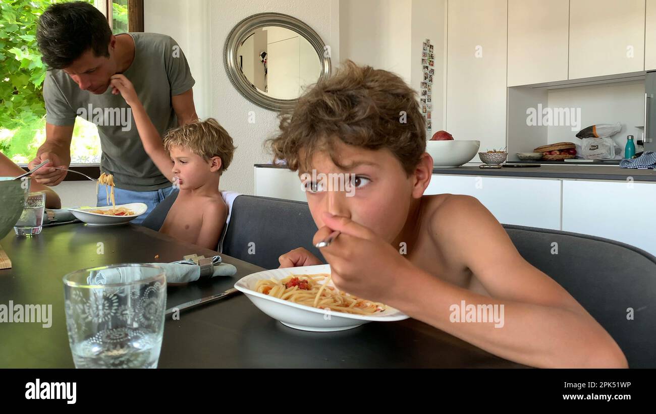 Family eating pasta spaghetti lunch together, father eating boy pasta ...