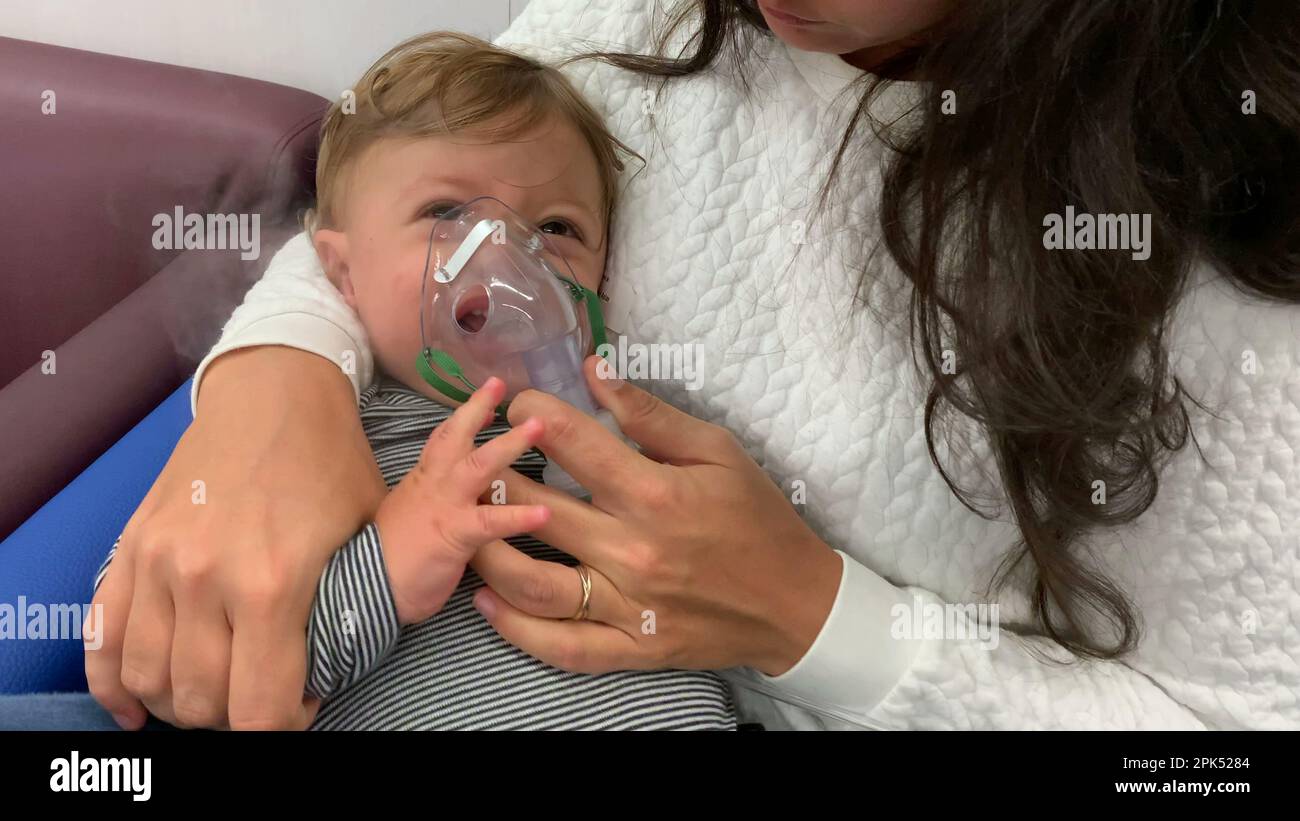 Mother giving respiratory inhaler to sick crying baby toddler Stock ...