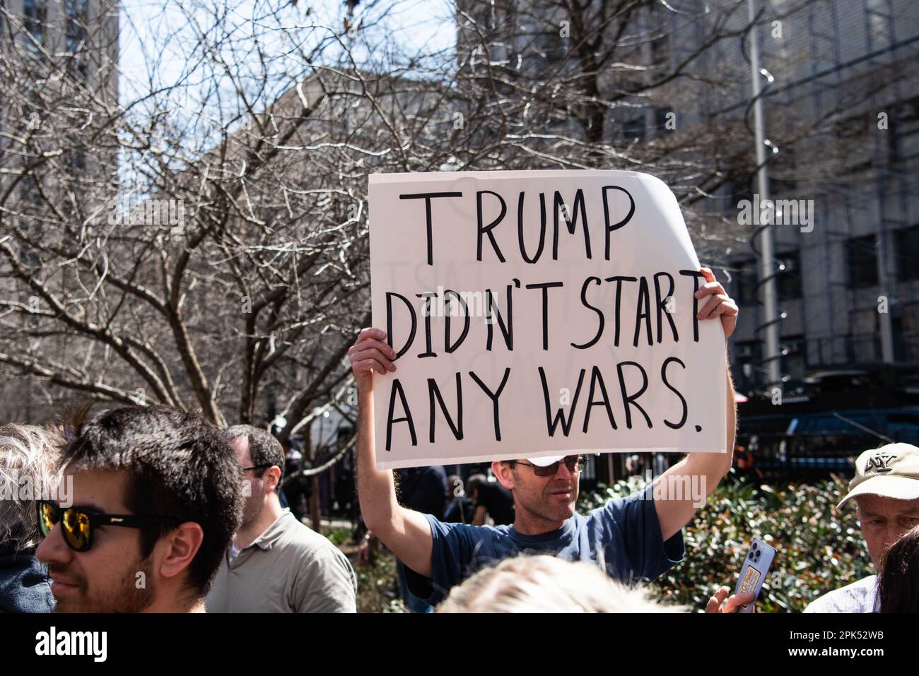 A man holding a sign saying "Trump didn't start any wars" at the ...