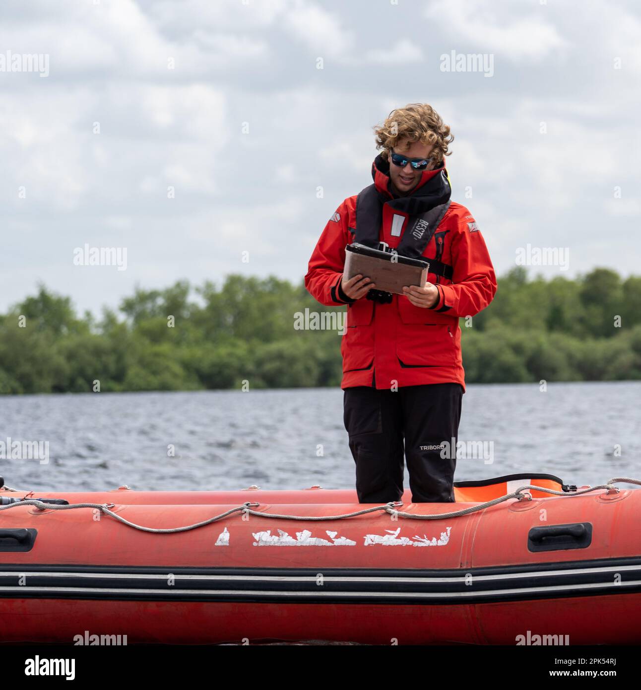 A Caucasian male stands confidently on a red inflatable raft in a body ...