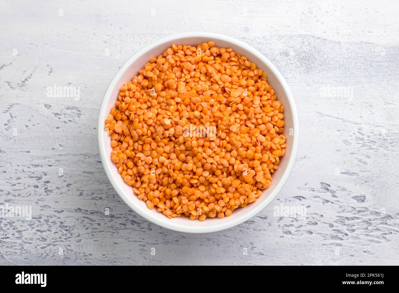 Raw soaked lentils in a white bowl on a light gray background, top view ...