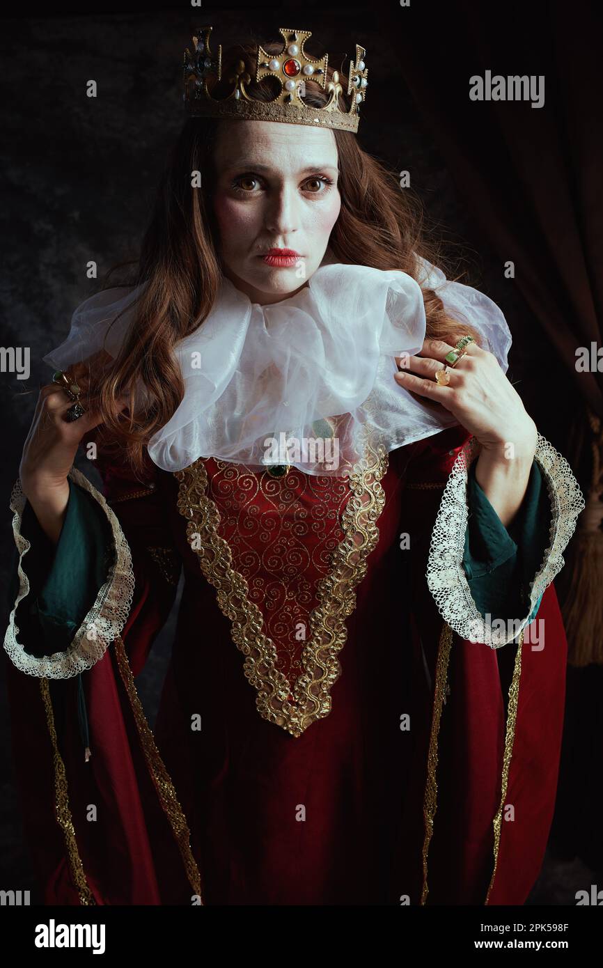 medieval queen in red dress with white collar and crown on dark gray ...
