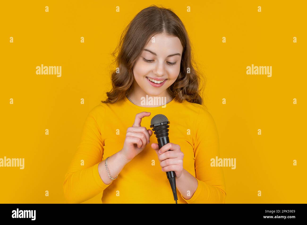 happy teen girl check mic on yellow background Stock Photo - Alamy