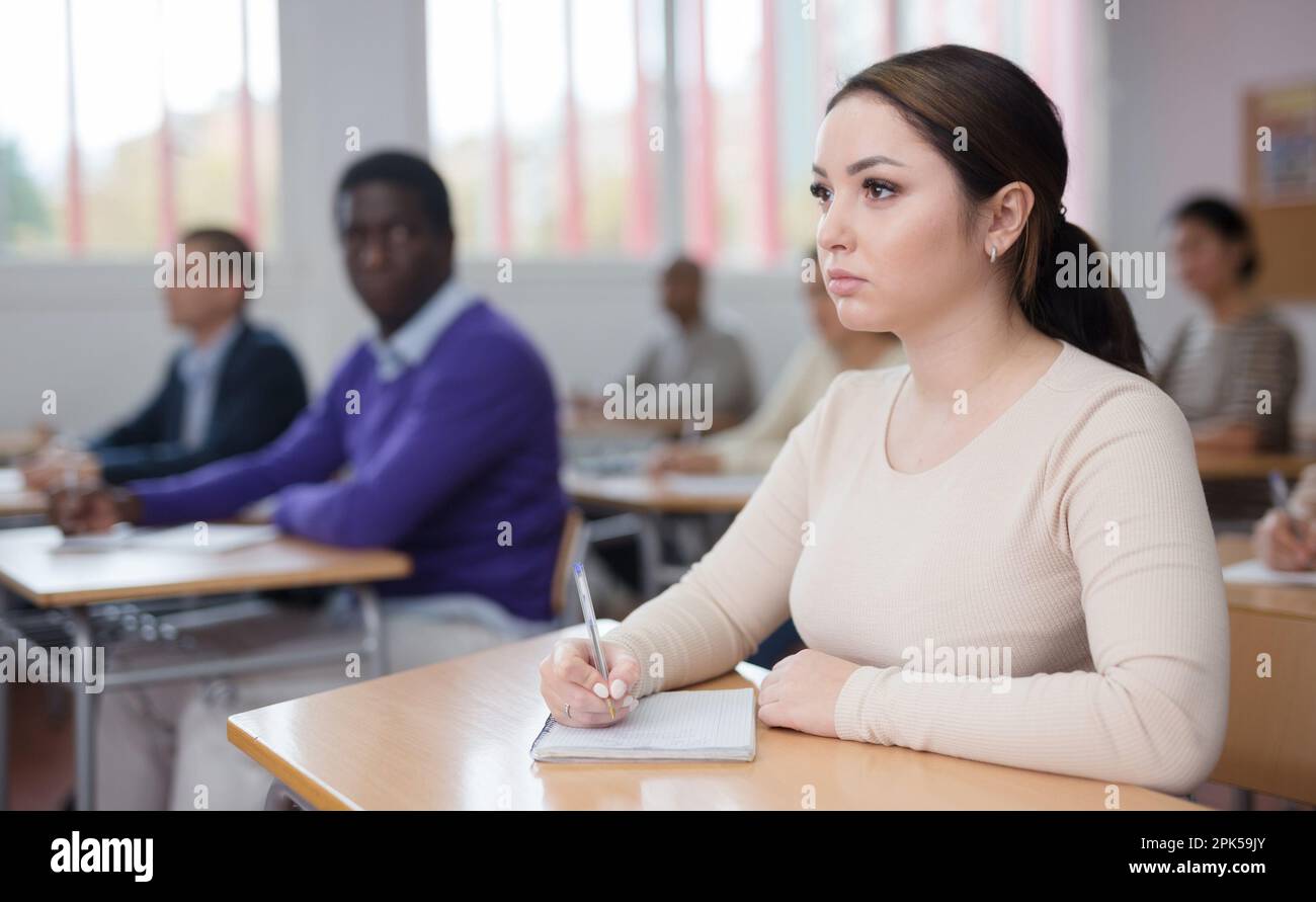 Young brunette listening to lecture in classroom with group Stock Photo ...