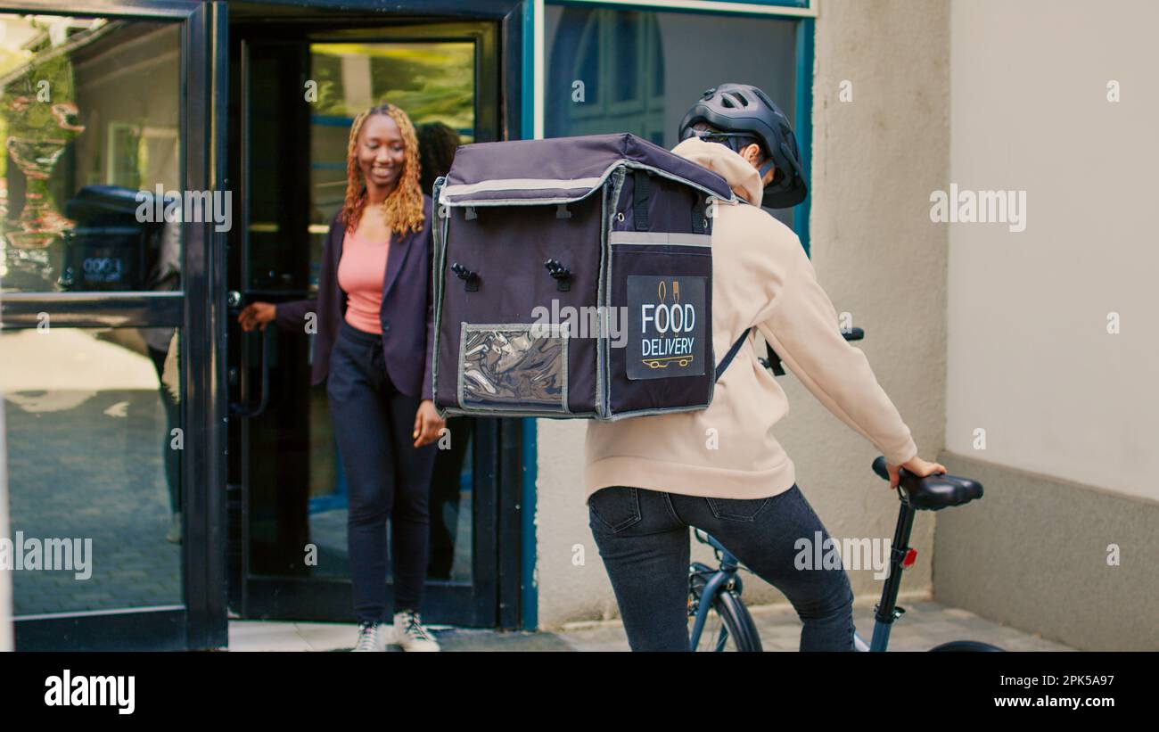 Fastfood delivery person giving meal order in package to african ...