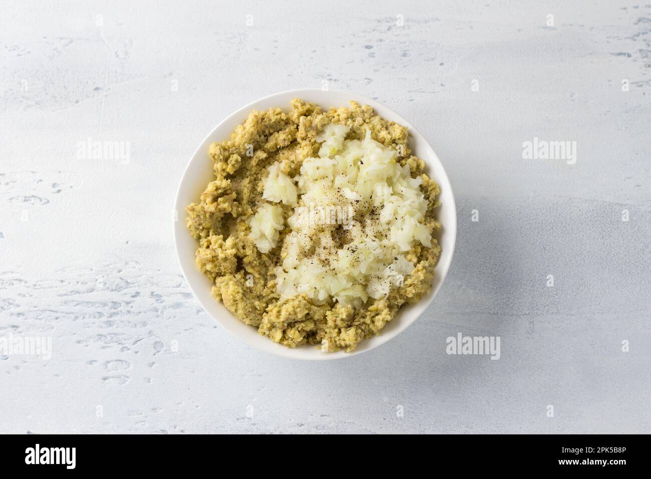 White bowl with soaked ground green lentils, onions and spices on a ...