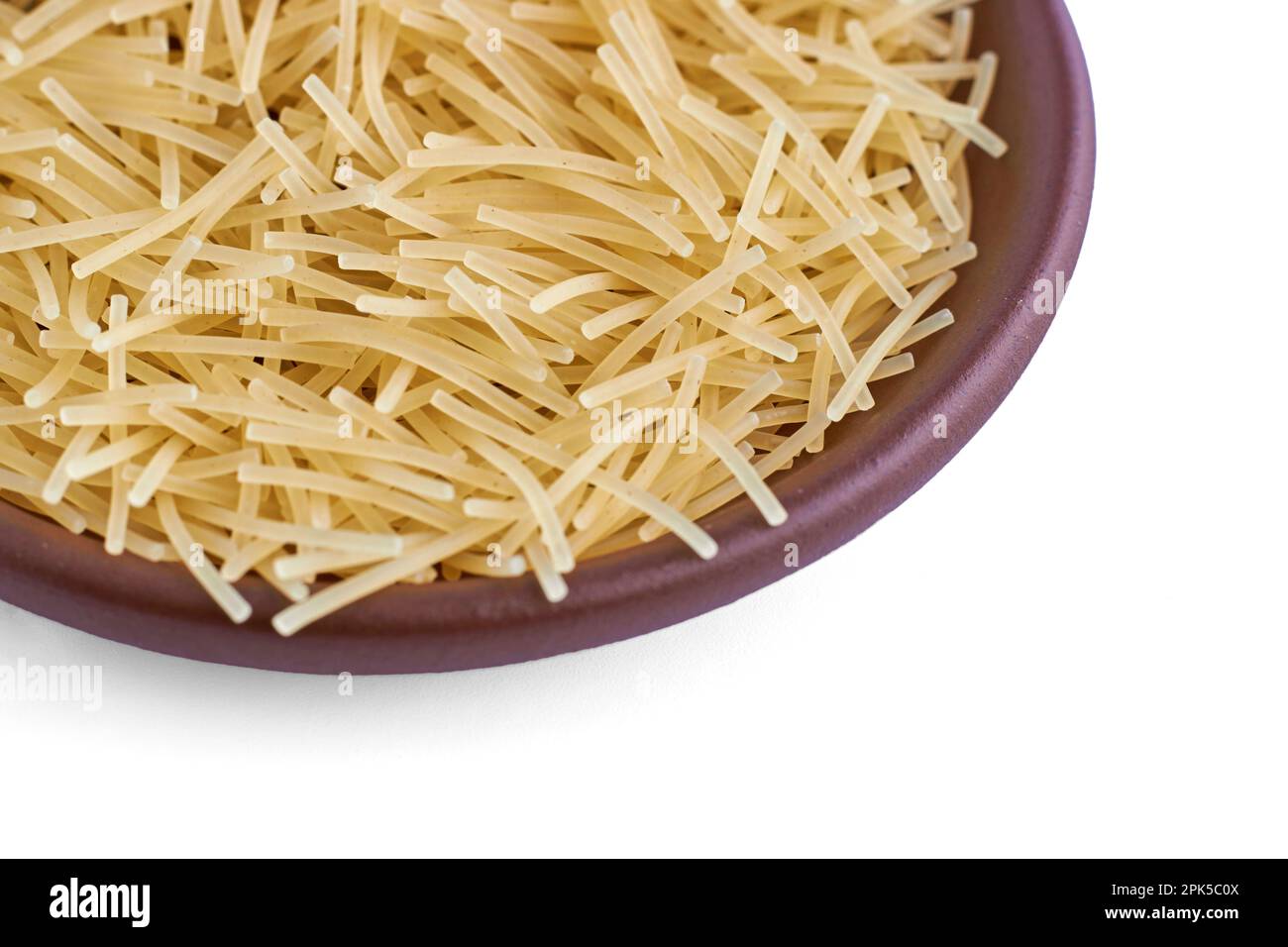 Pasta noodles in a clay ceramic bowl close-up isolated on a white ...