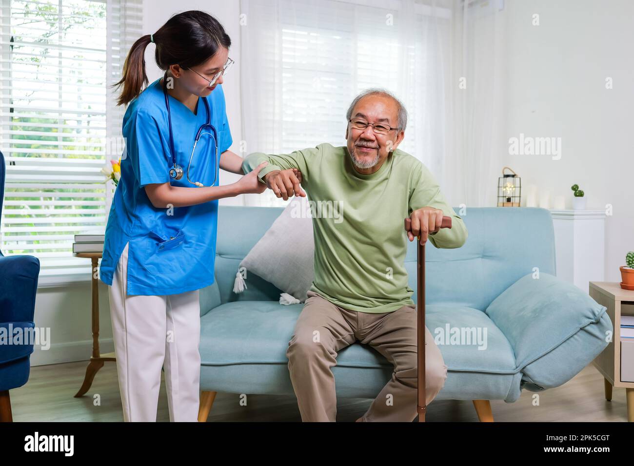 Elderly patient on sofa trying to stand and walking with caregiver nurse Stock Photo - Alamy