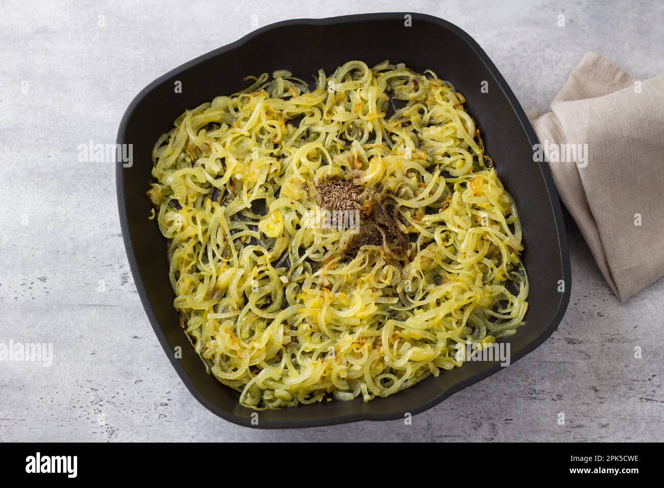 Non-stick frying pan with fried onions and spices: cumin and black ...