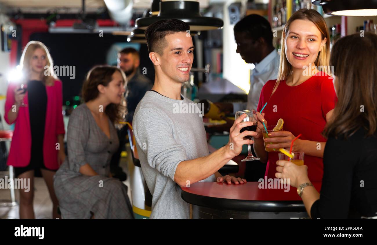 Man flirting with women on party, drinking cocktails at nightclub Stock ...