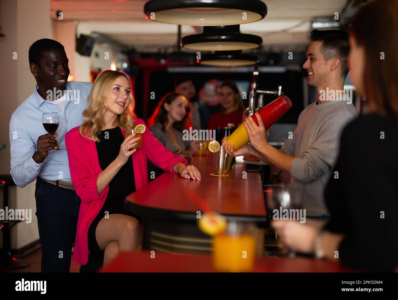 Man bartender shaking cocktail mixer for young people Stock Photo - Alamy