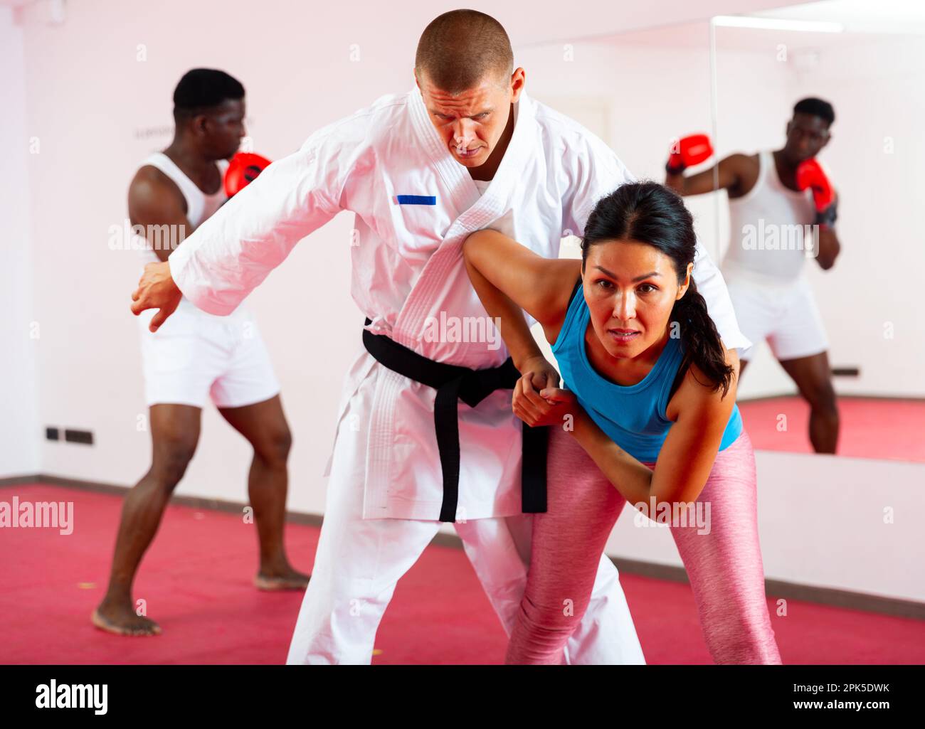 Woman is practicing self-defence fight in pair with trainer in gym ...