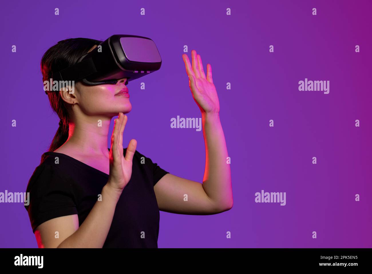 Asian woman using vr headset in studio with purple light and copy space ...