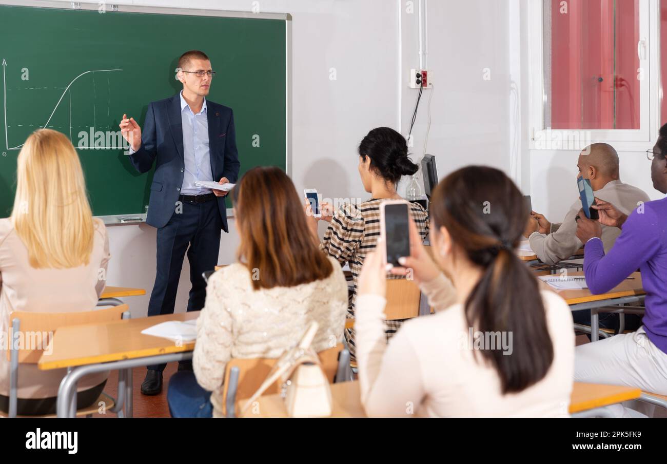 Teacher explaining new theme to adult students Stock Photo - Alamy