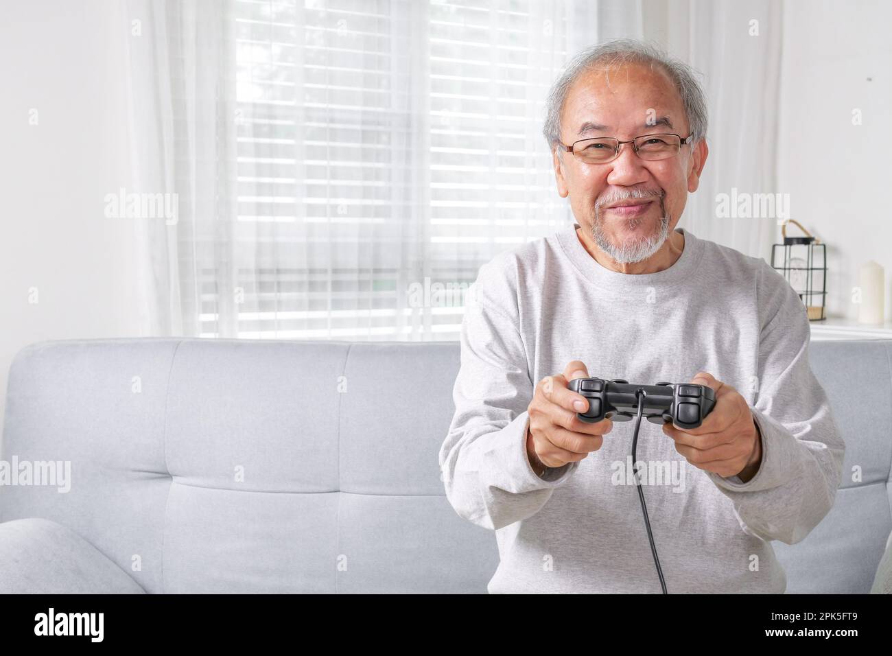 Senior elderly laughing on sofa using controller play game Stock Photo ...
