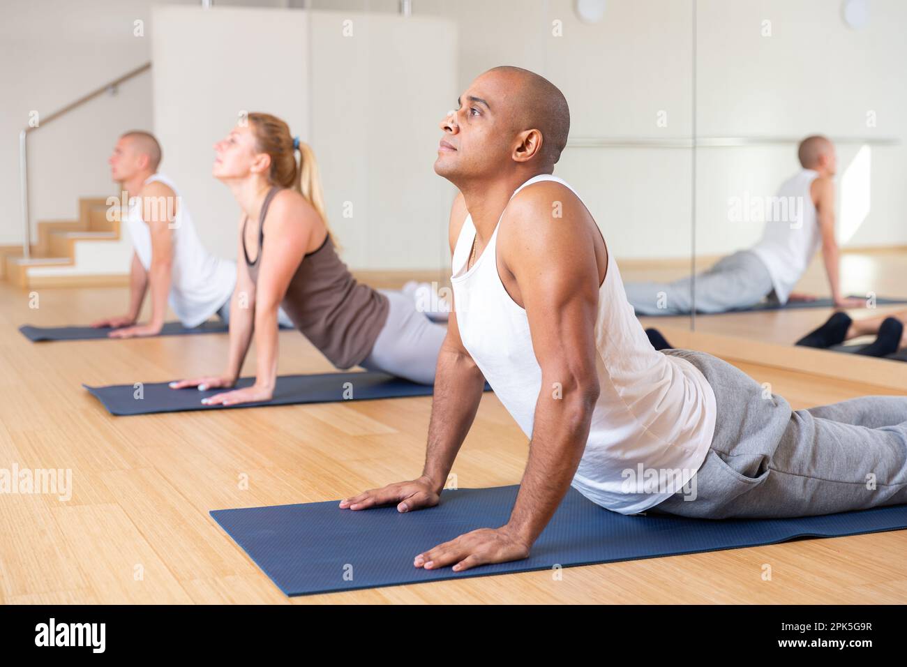 Nice people exercising during yoga class in fitness center Stock Photo ...