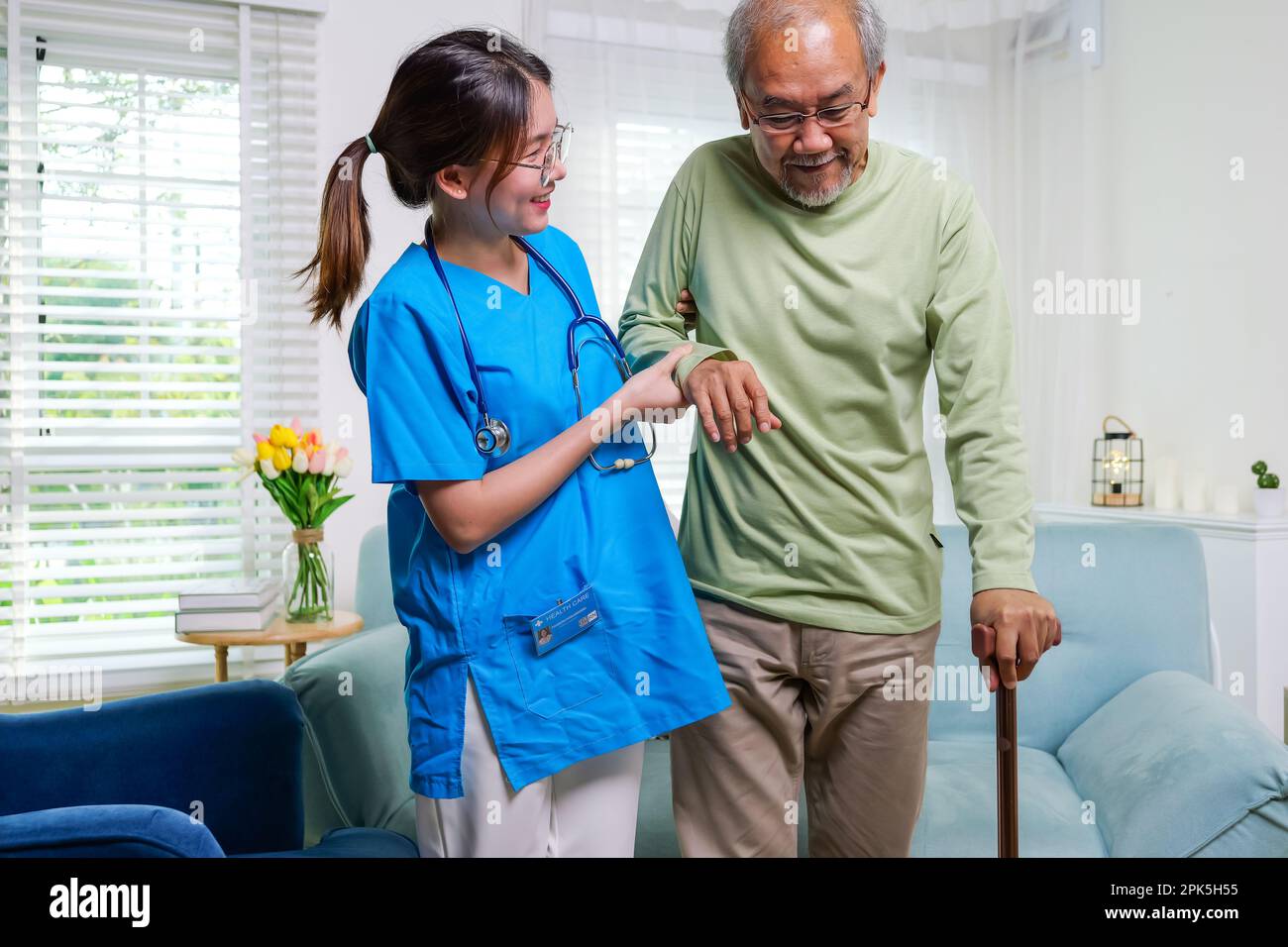 Elderly patient on sofa trying to stand and walking with caregiver nurse Stock Photo - Alamy