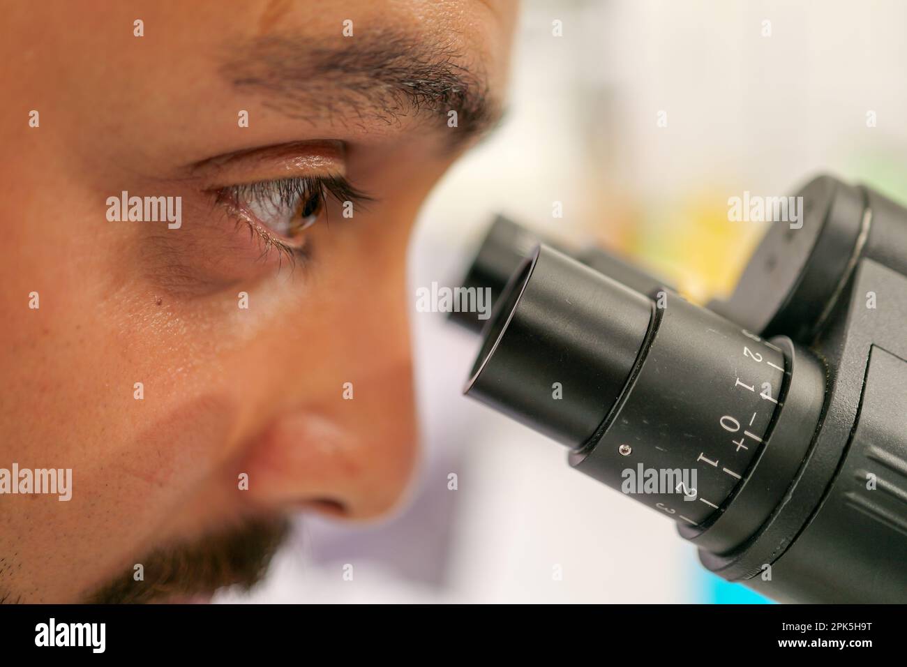 Eye of professional male scientist looking through microscope in ...