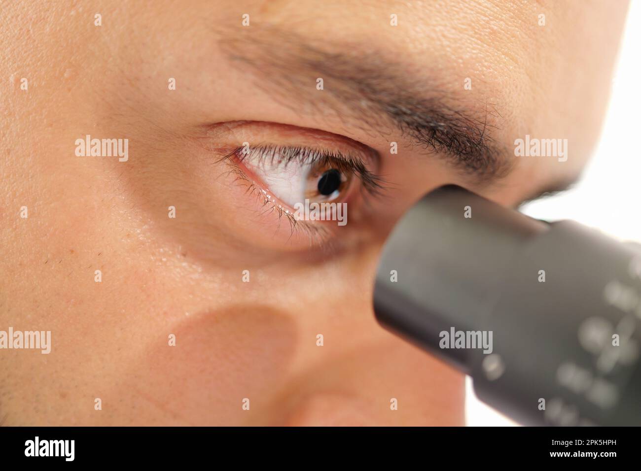 Eye of professional male scientist looking through microscope in ...