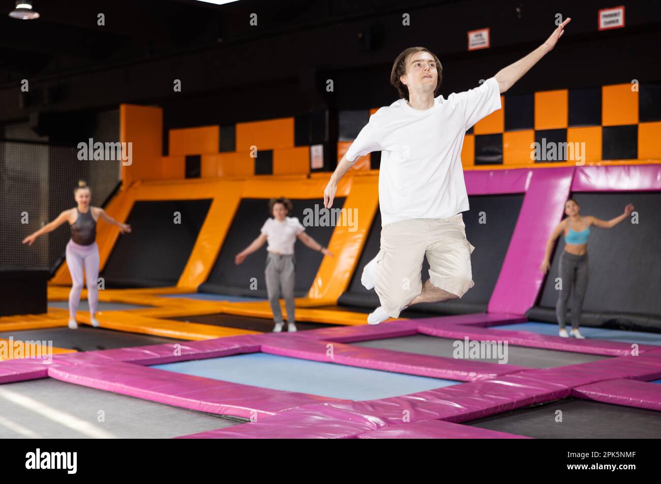 Young guy trains jumping in trampoline center Stock Photo - Alamy