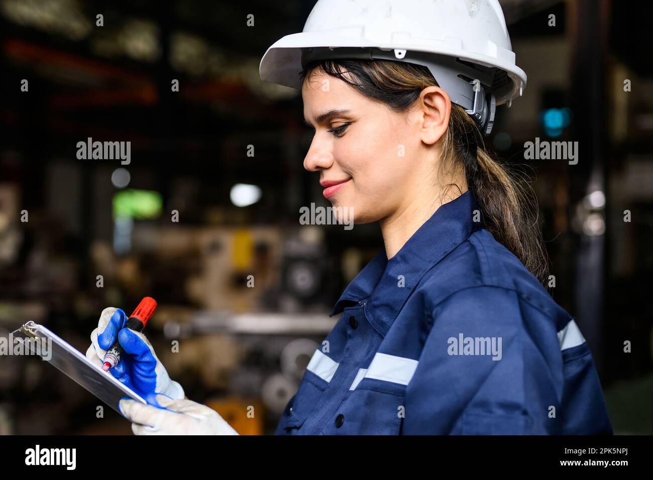 Happy female mechanical engineer repairing engine machine at factory ...