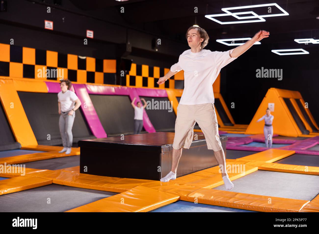 Young man in sport clothes high jumping in trampoline arena Stock Photo ...