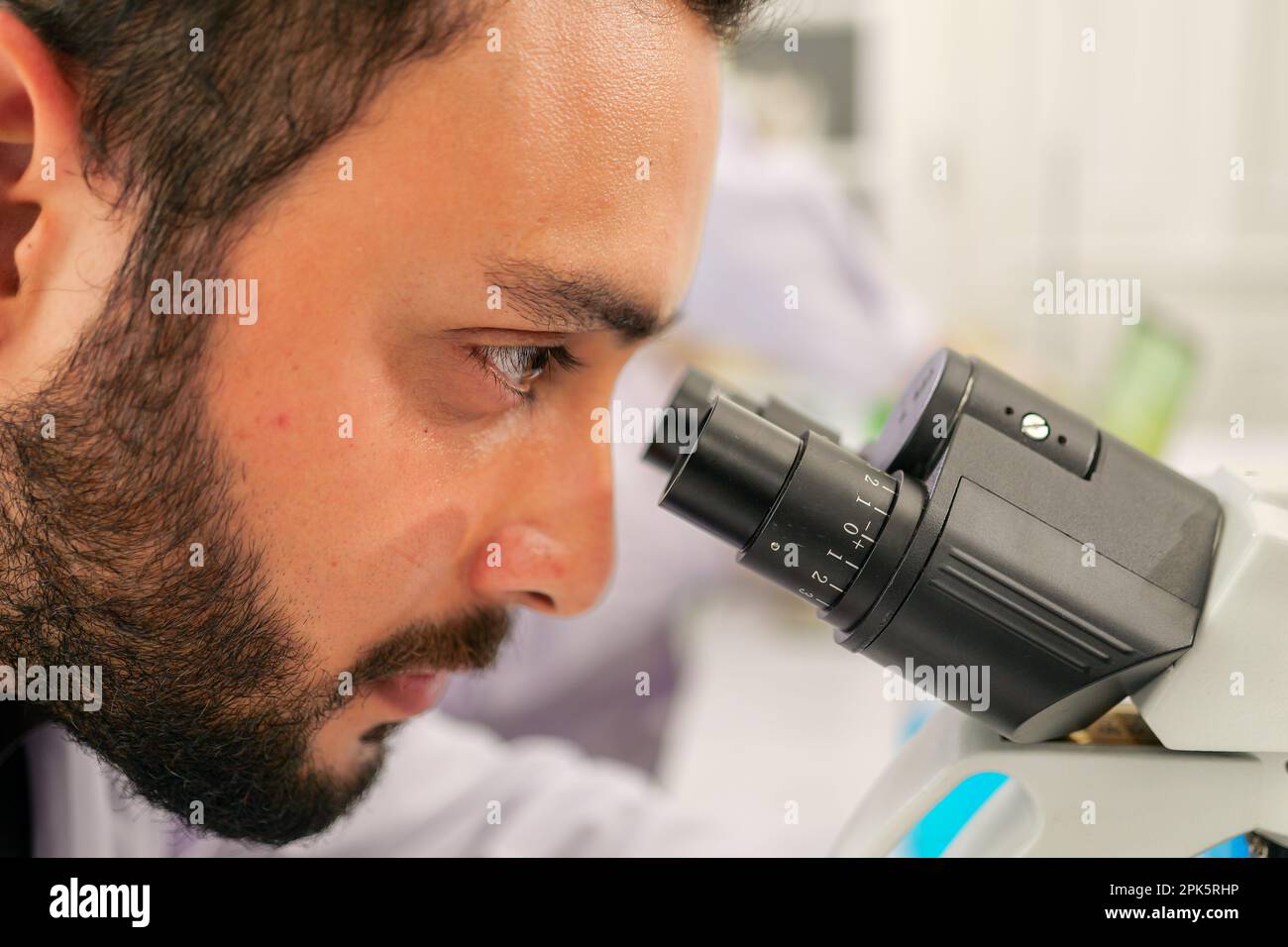 Eye of professional male scientist looking through microscope in ... Eye of professional male scientist looking through microscope in ...