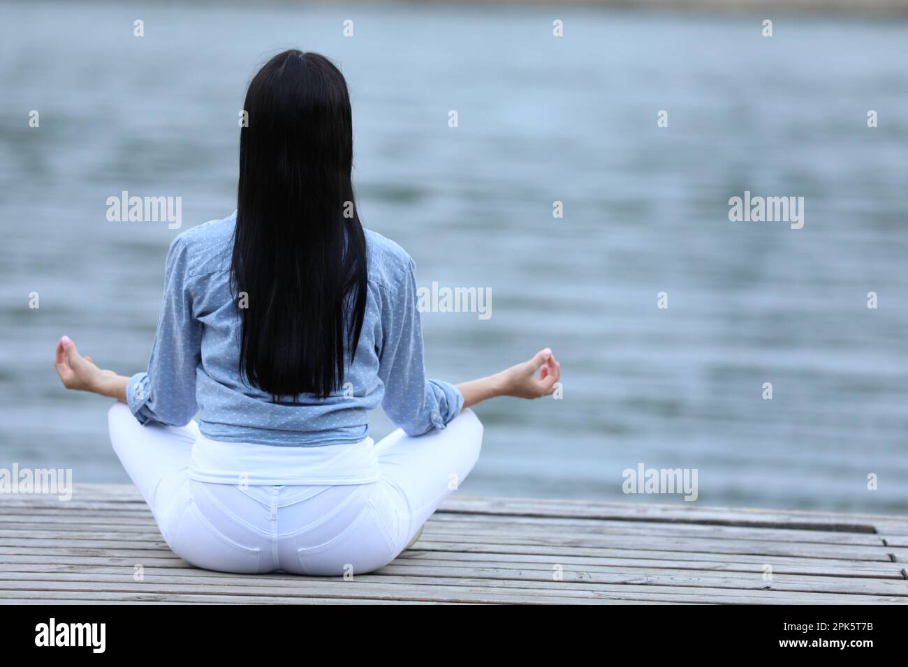 Young woman meditating near river, back view. Space for text Stock ...