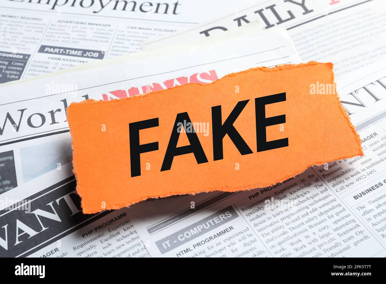 Orange paper piece with word FAKE on pile of newspapers, closeup Stock ...