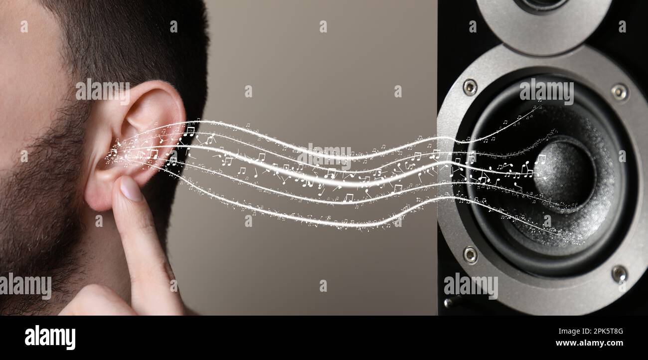 Modern audio speaker and man listening to music on light grey ...