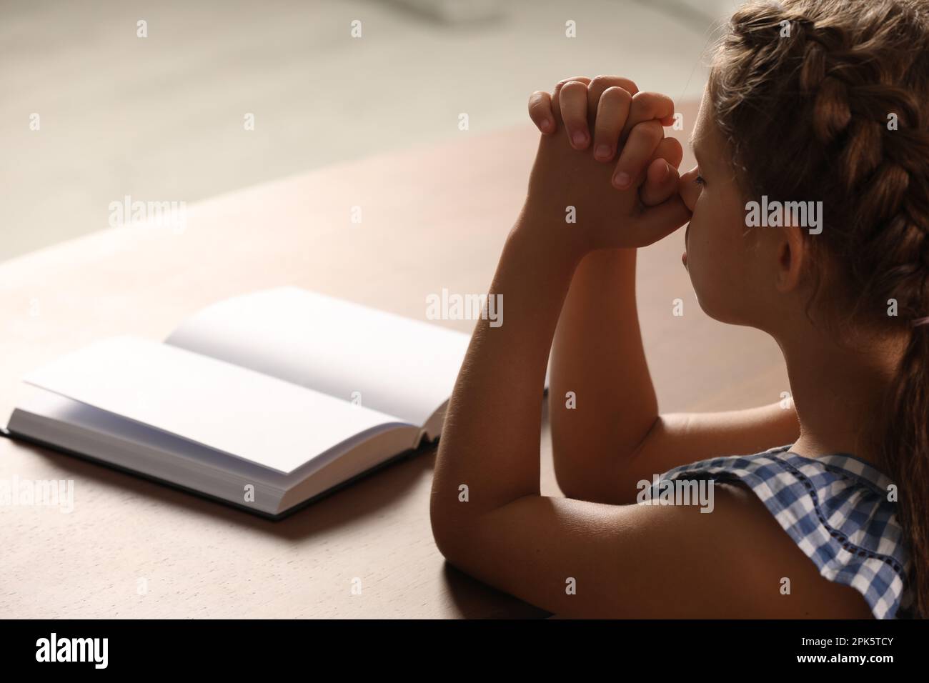 Cute little girl praying over Bible at table indoors, closeup Stock ...