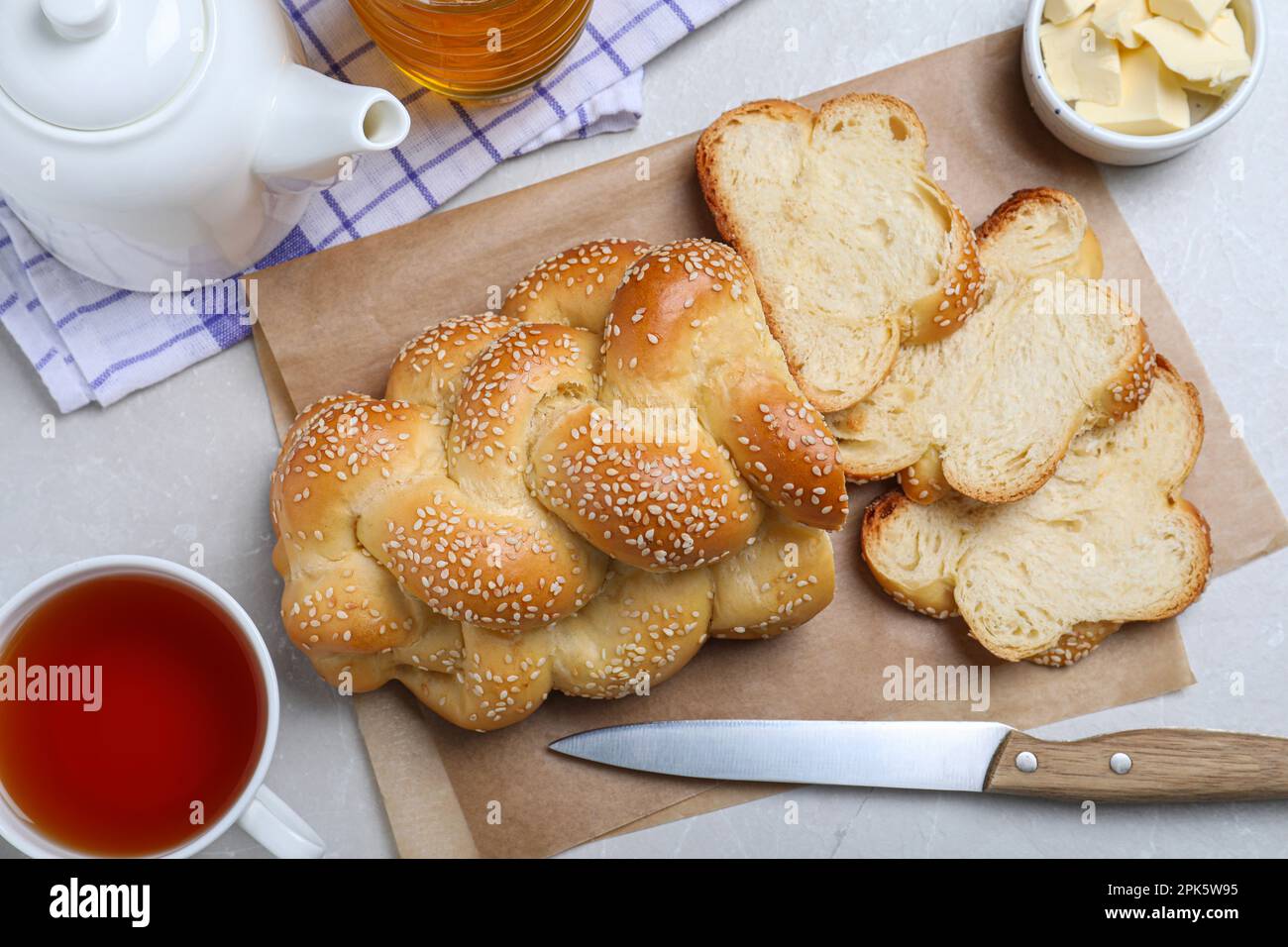 Cut homemade braided bread and freshly brewed tea on light grey table ...