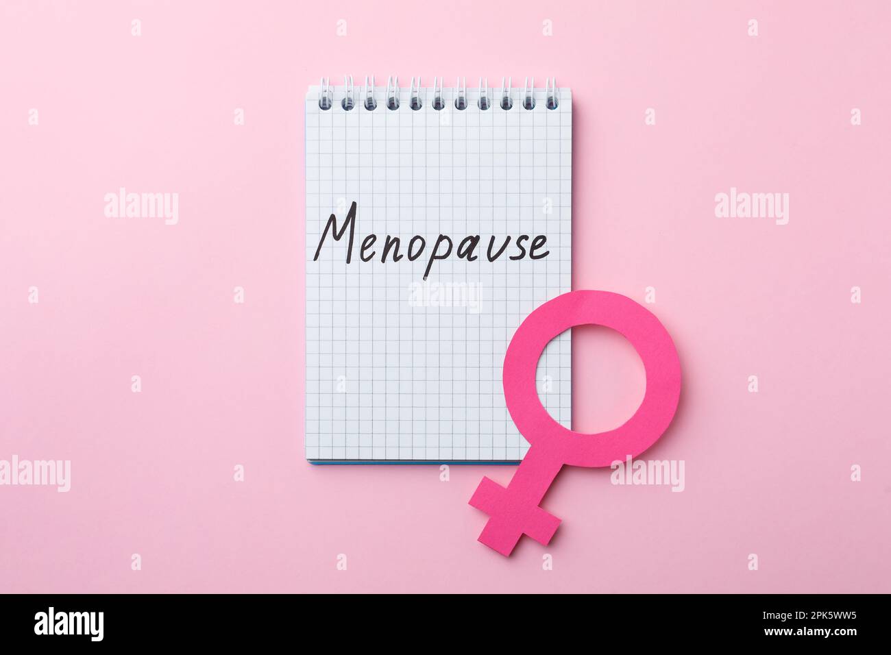 Notebook with word Menopause and female gender sign on pink background ...