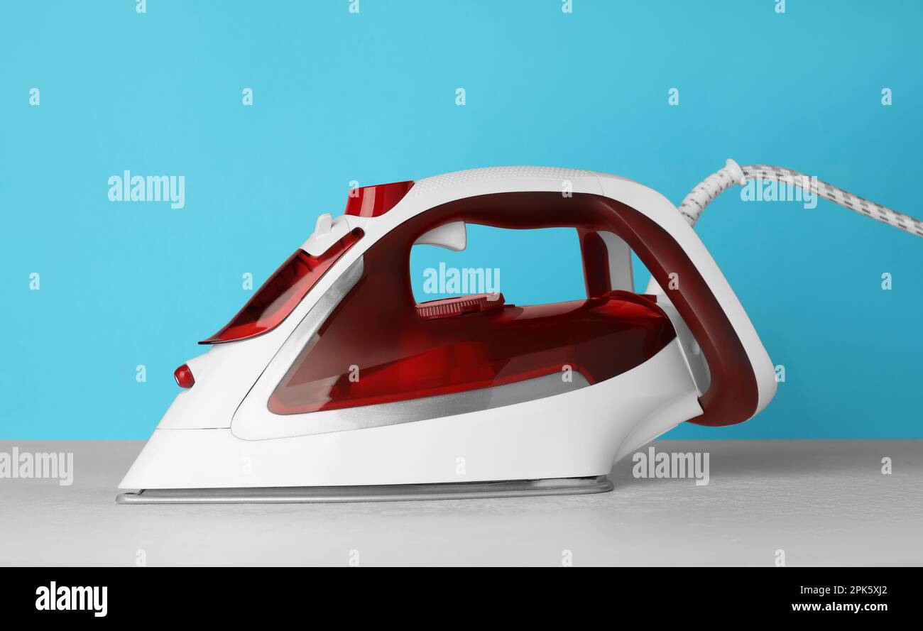 One modern iron on light blue background. Home appliance Stock Photo ...