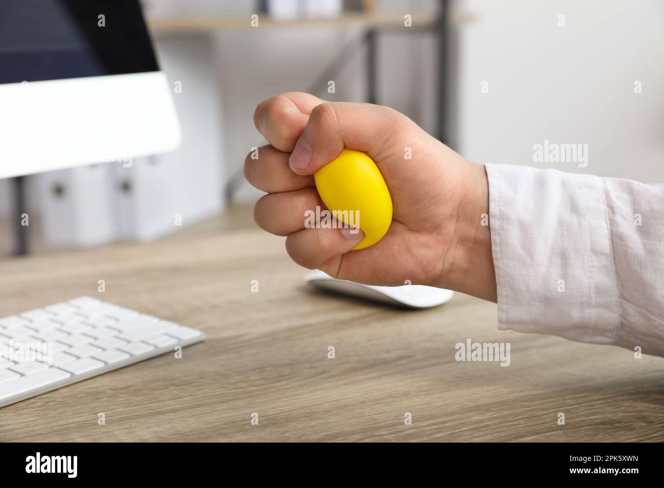 Man squeezing yellow stress ball in office, closeup Stock Photo - Alamy