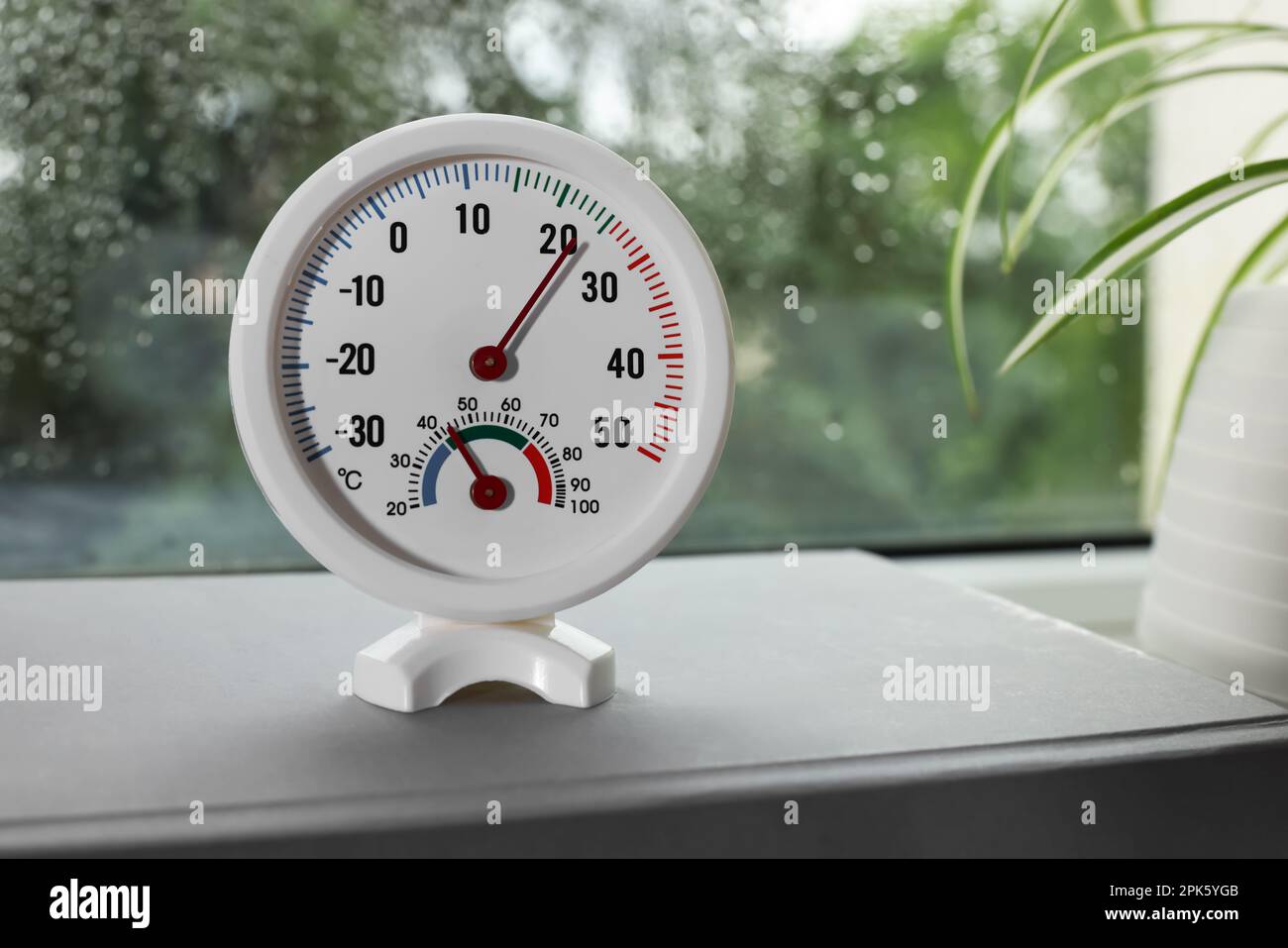 Round mechanical hygrometer on book near window. Space for text Stock ...