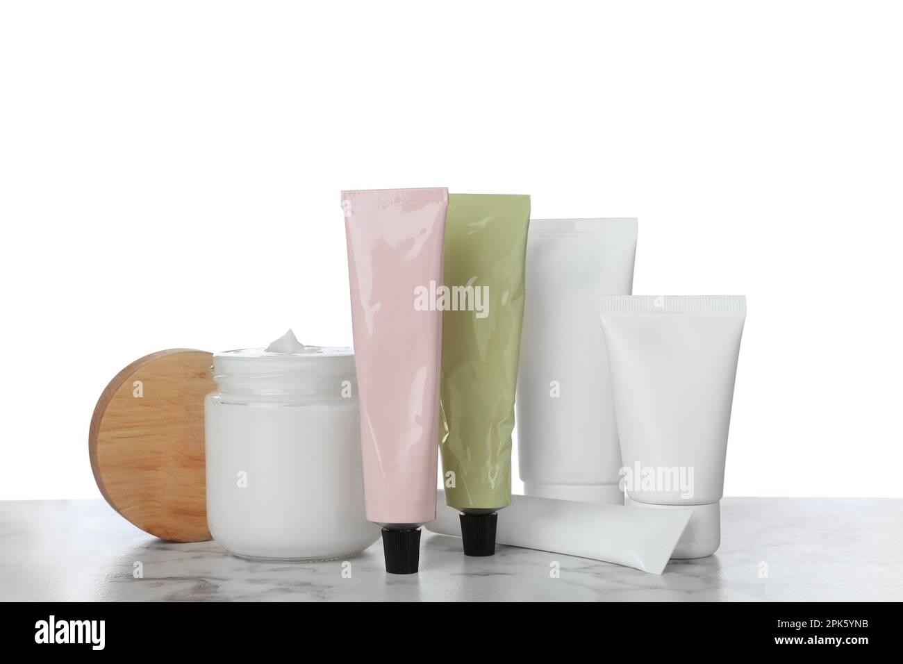 Set of cosmetic products in jar and tubes on marble table against white ...