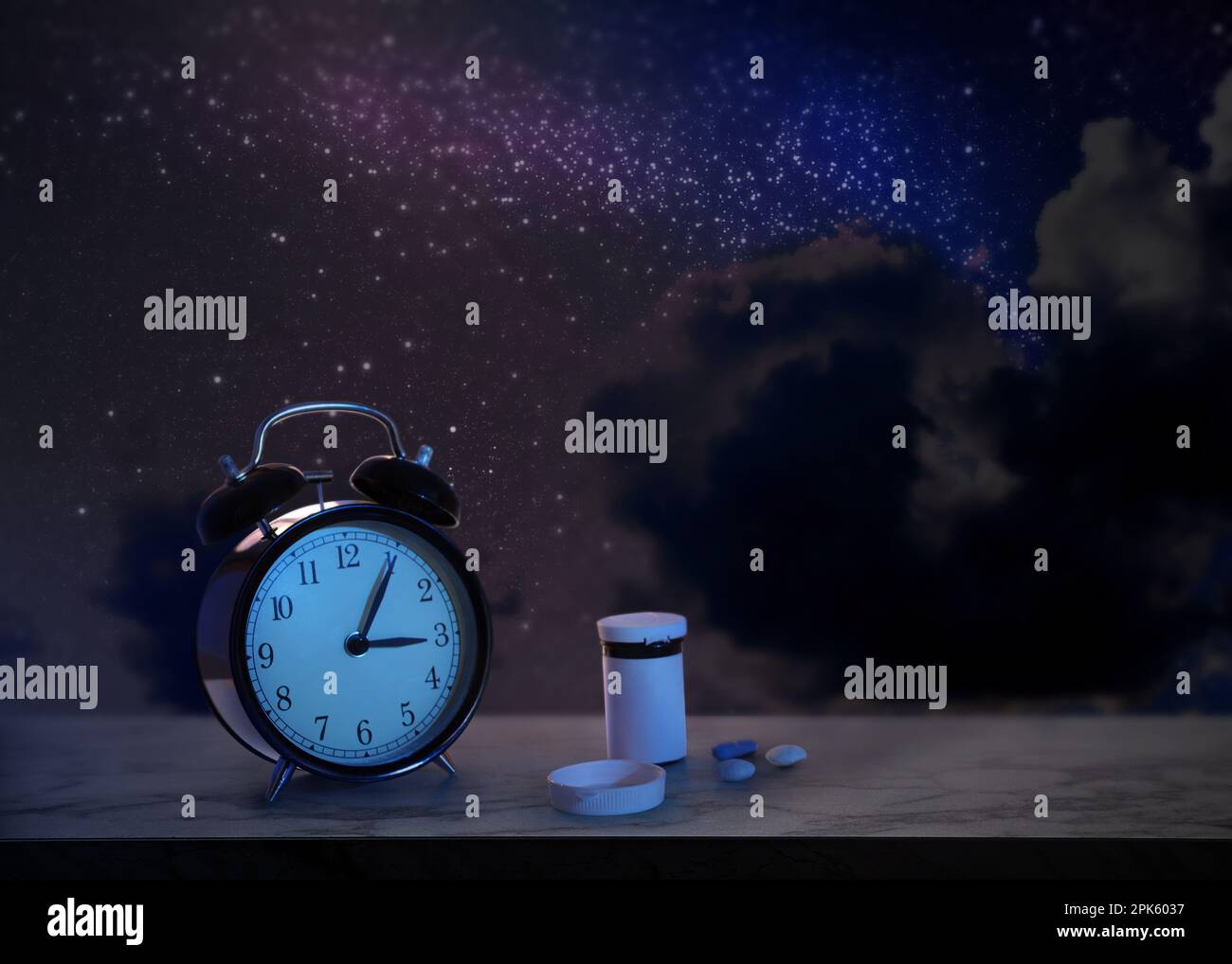 Alarm clock and soporific pills on grey table against night sky with ...