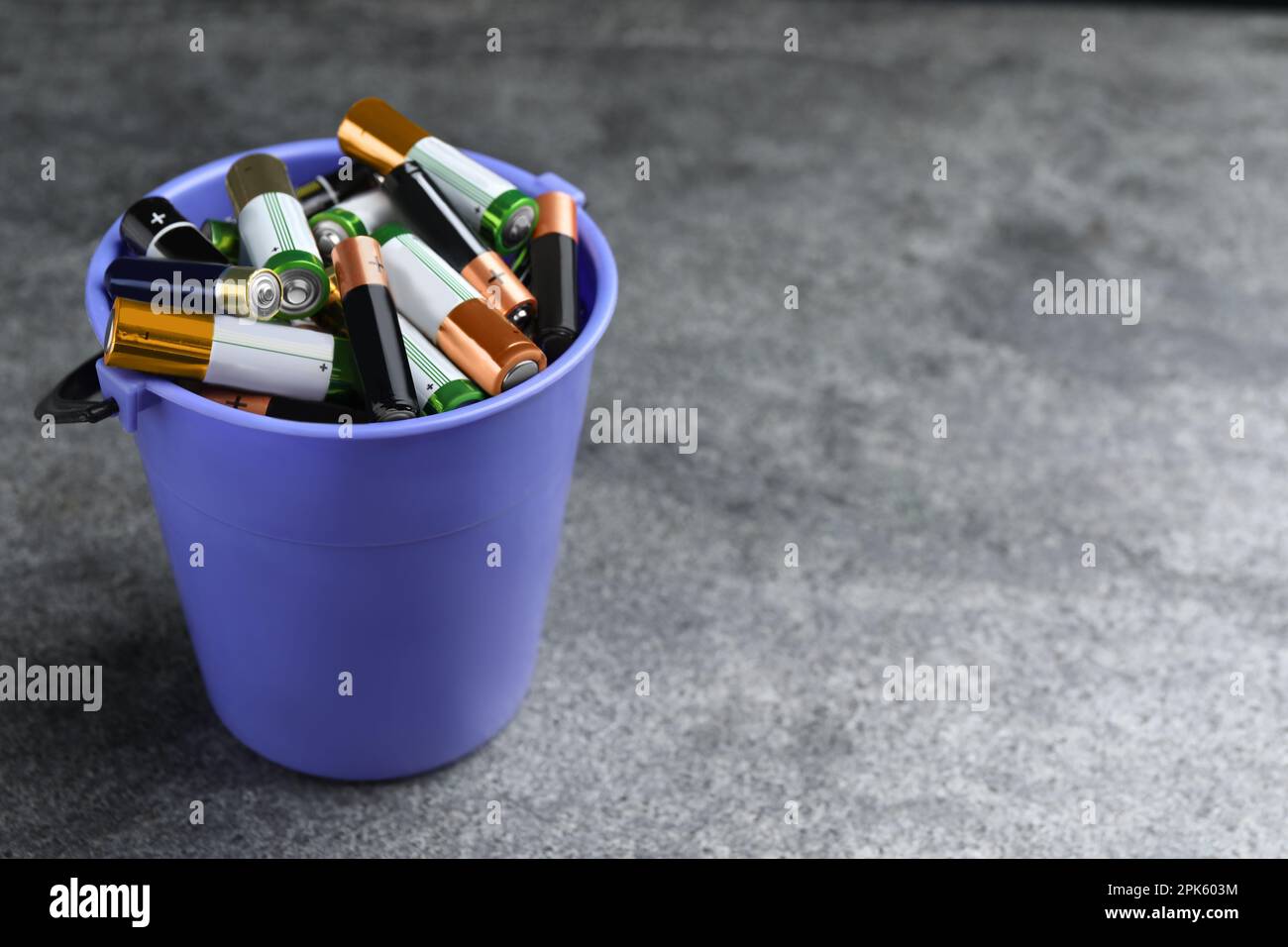 Used batteries in bucket on grey table, space for text Stock Photo - Alamy
